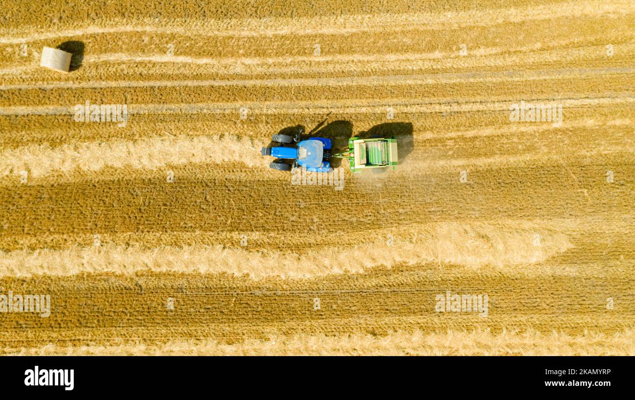 Above top view on tractor as pulling round baler, machine that rolls up ...