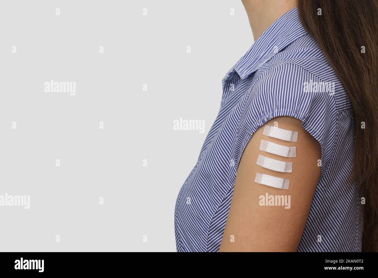 Four medical plasters on the arm of a young woman. Symbol of four doses ...