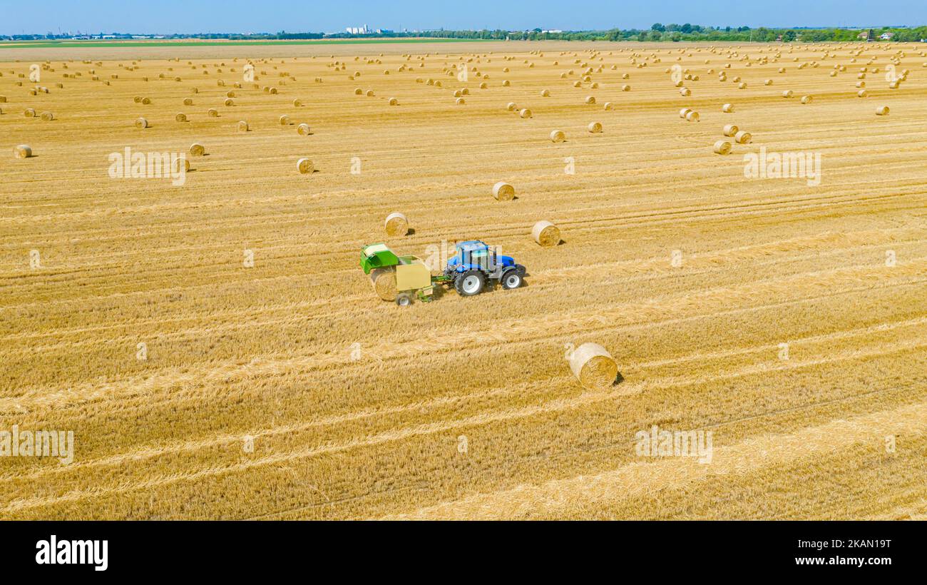 Above view on tractor as pulling round baler, machine that rolls up the ...