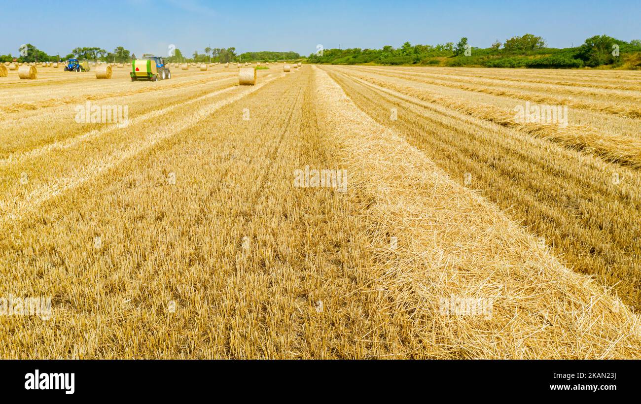 Above view on tractor as pulling round baler, machine that rolls up the ...