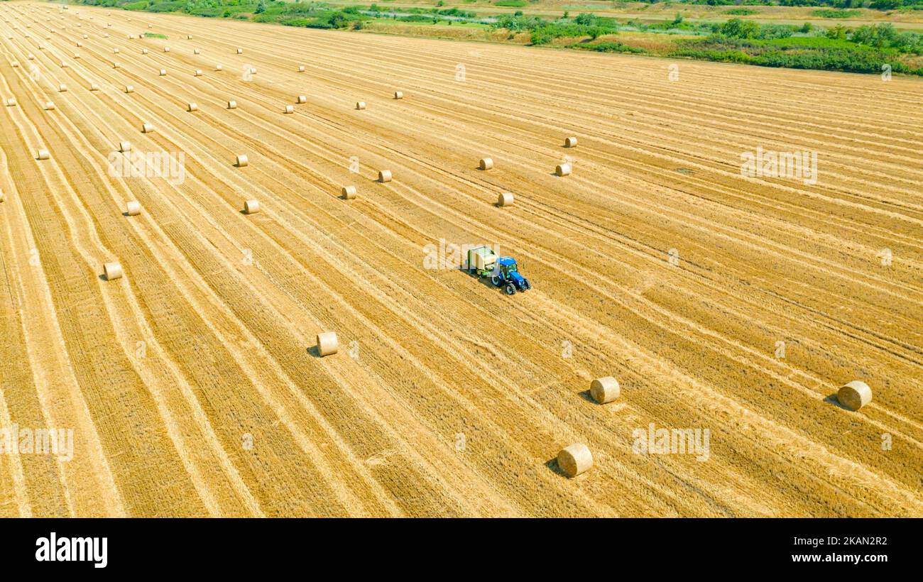 Above view on tractor as pulling round baler, machine that rolls up the ...