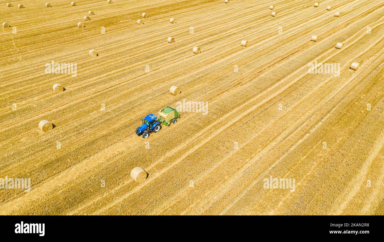 Above view on tractor as pulling round baler, machine that rolls up the ...