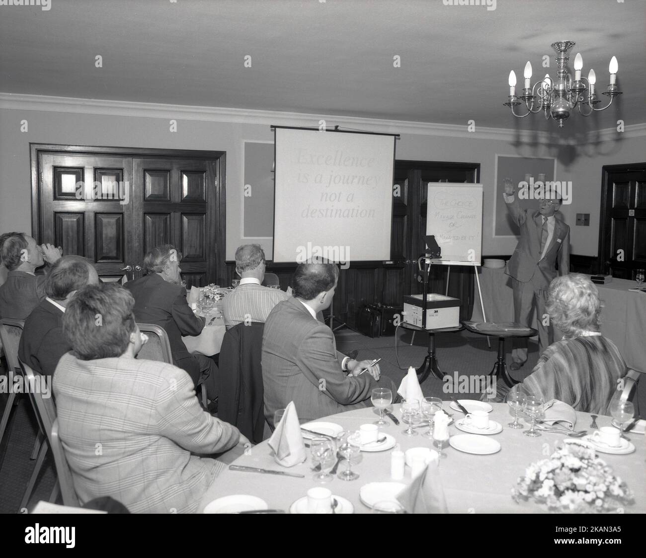 1980s, historical, in a hotel room, male trainer, presenter, with ...
