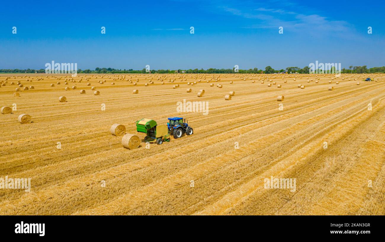Above view on tractor as pulling round baler, machine that rolls up the ...