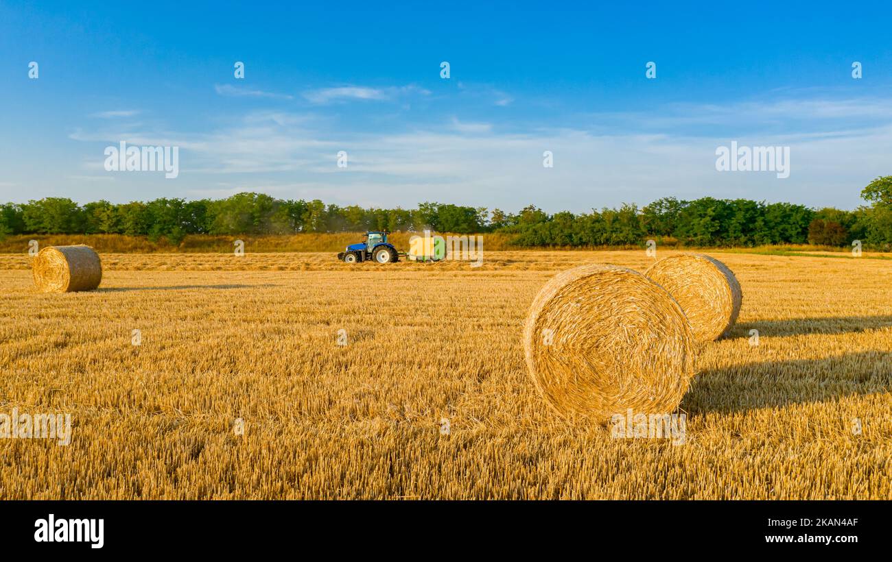 Above view round bale of straw after harvest, in background tractor is ...