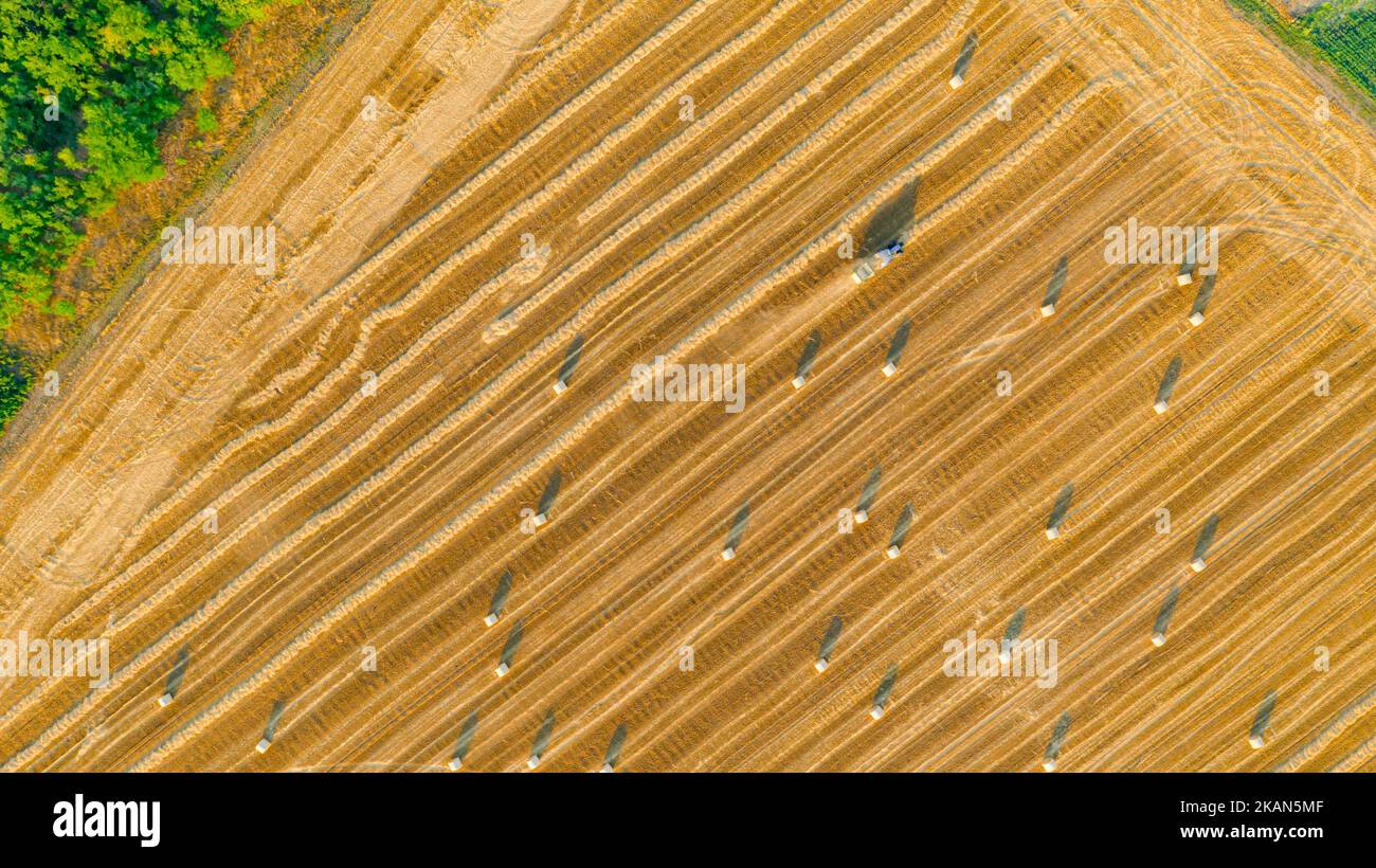 Above top view on tractor as pulling round baler, machine that rolls up ...