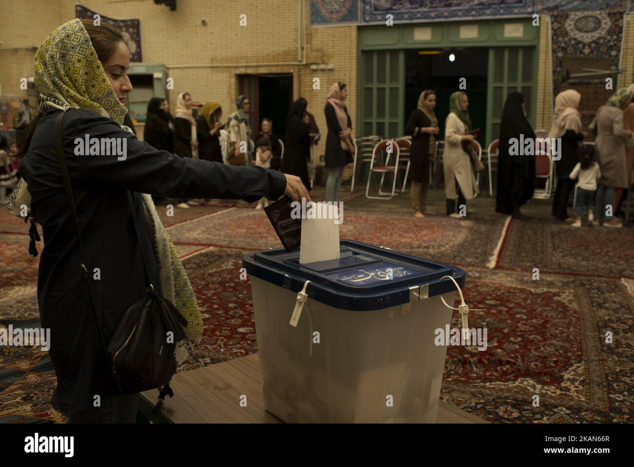 A voter is putting her ballot paper into the ballot box at a polling ...