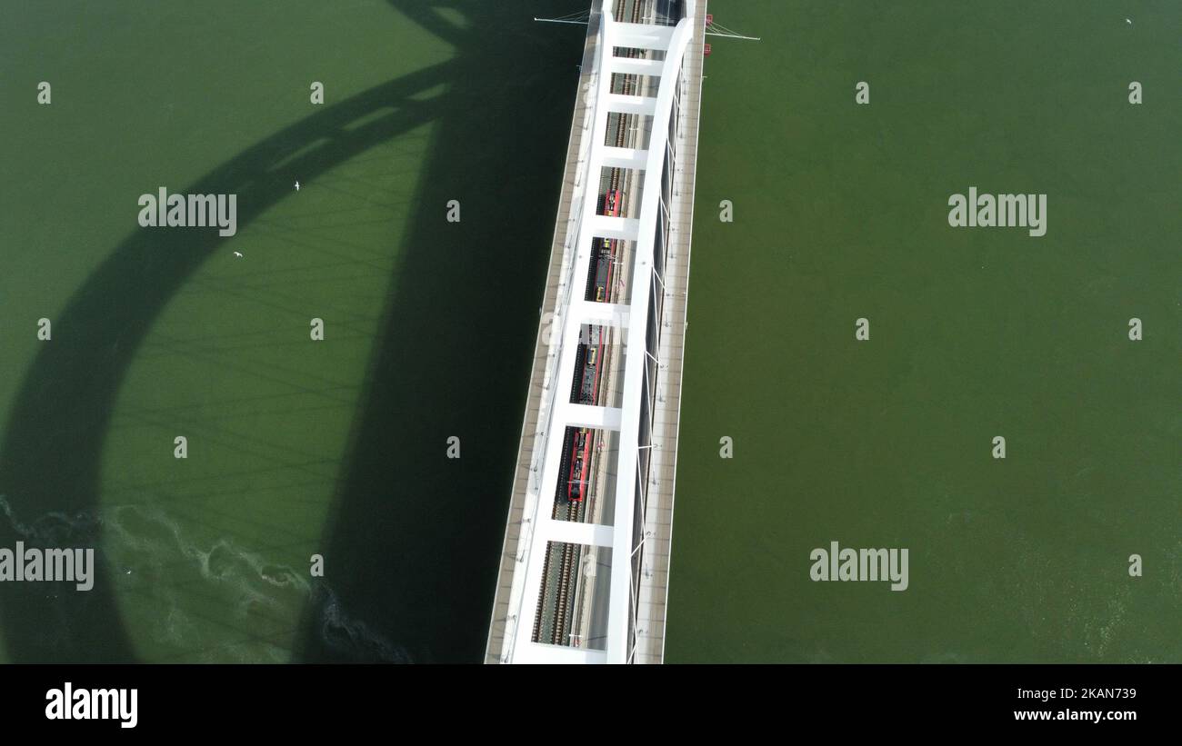 An aerial view of a white bridge over the river with a moving train ...