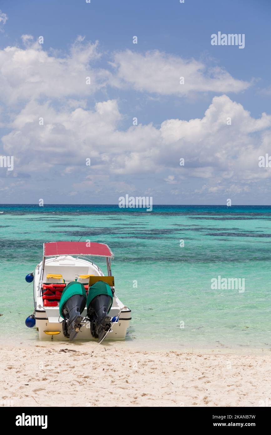 A vertical shot of a small boat on the beach with sea and cloudy blue ...