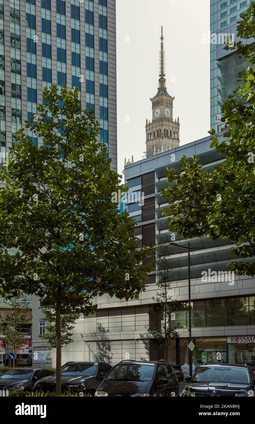 The tower with a spire and a clock. The building is between skyscrapers ...