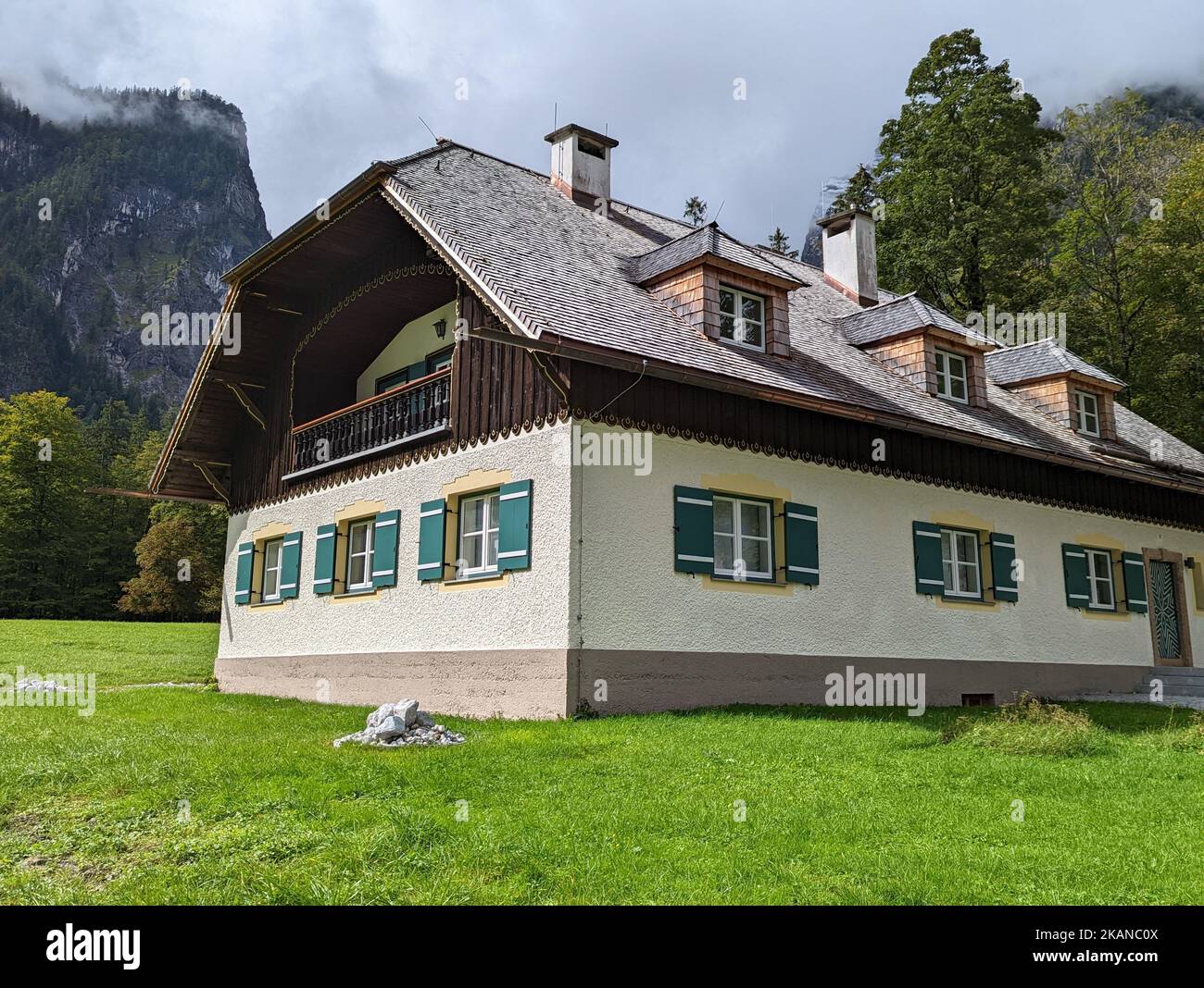 A traditional alpine Bavarian house on meadow with mountain, trees and ...