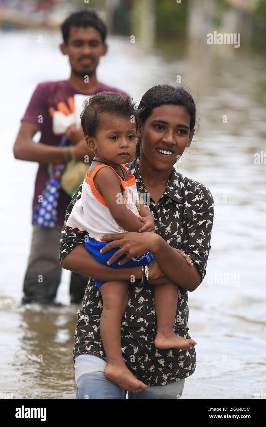 A Srilankan woman walks through a flooded road with her baby in ...