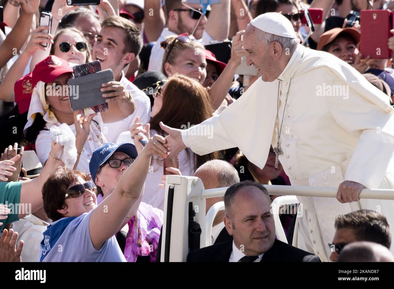 A faithful touches Pope Francis' hand as he is driven through the crowd ...
