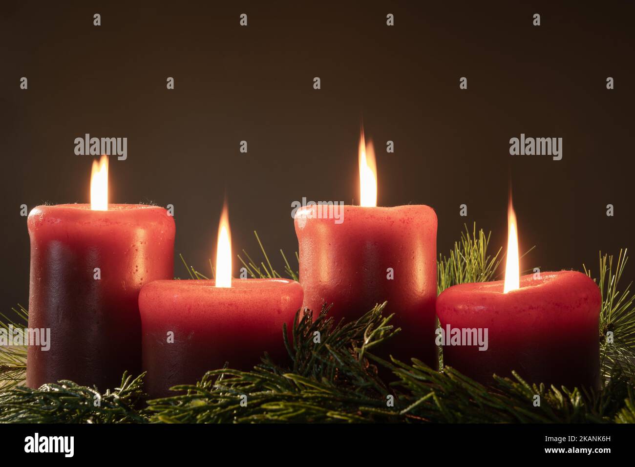 Advent wreath with four red candles lit and glowing in a dark room with ...