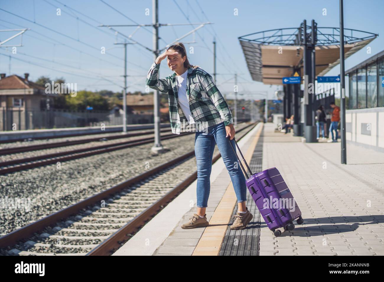 Happy woman looking away while waiting for her train on a railroad ...
