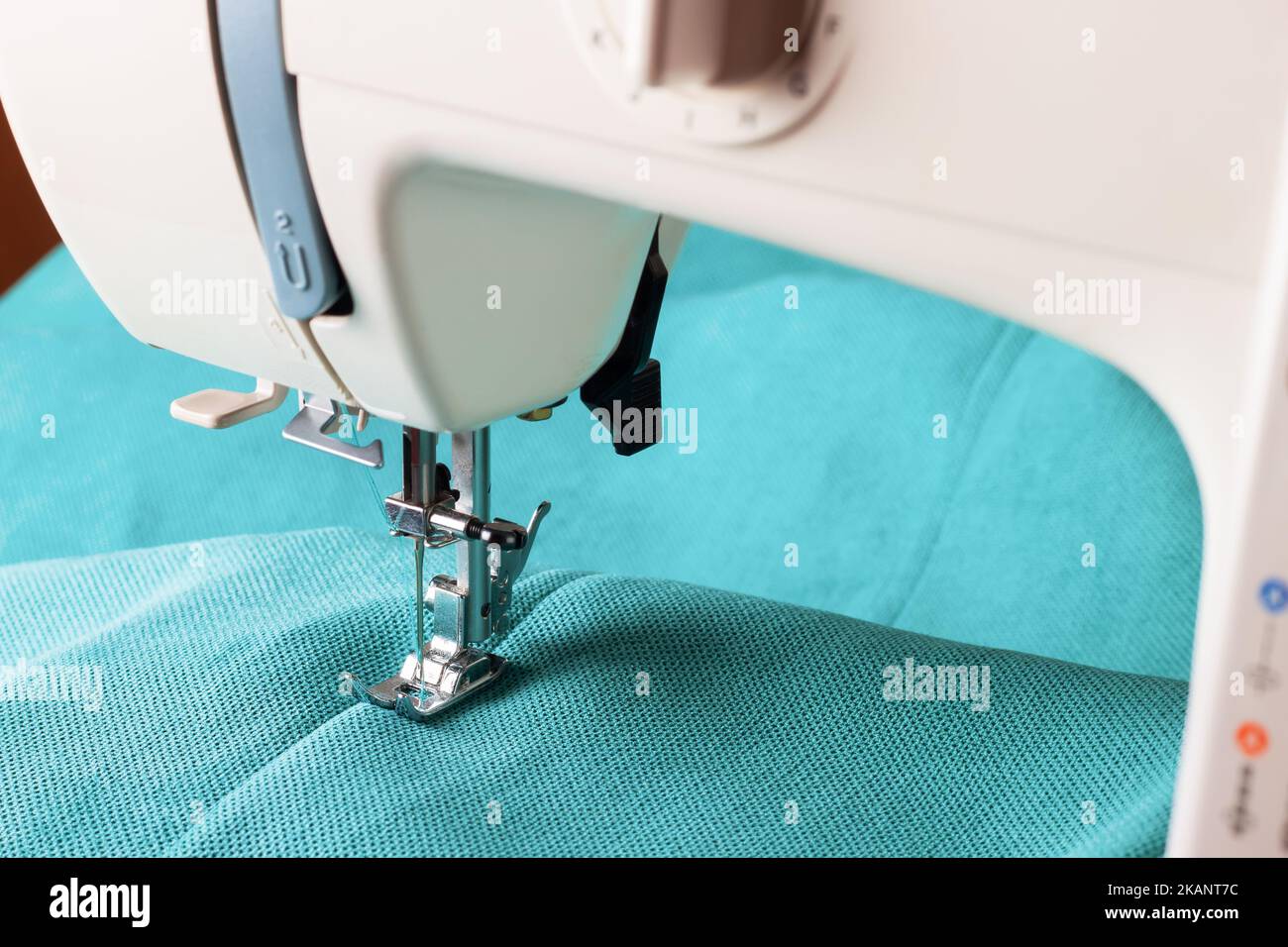 Modern sewing machine working with turquoise fabric. Sewing process ...