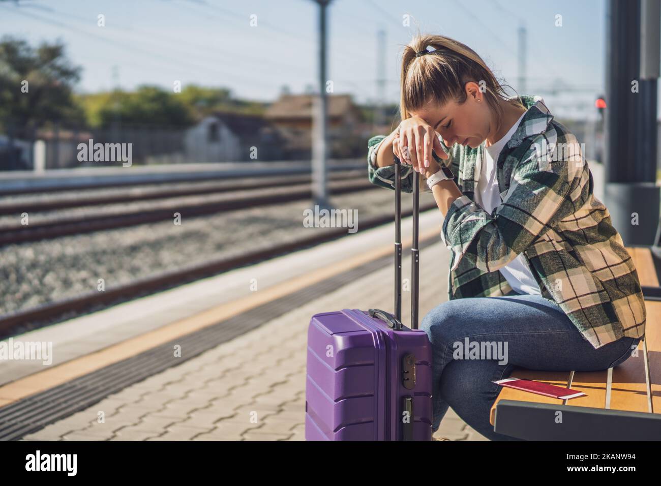 Worried woman sitting on a bench at the train station Stock Photo - Alamy