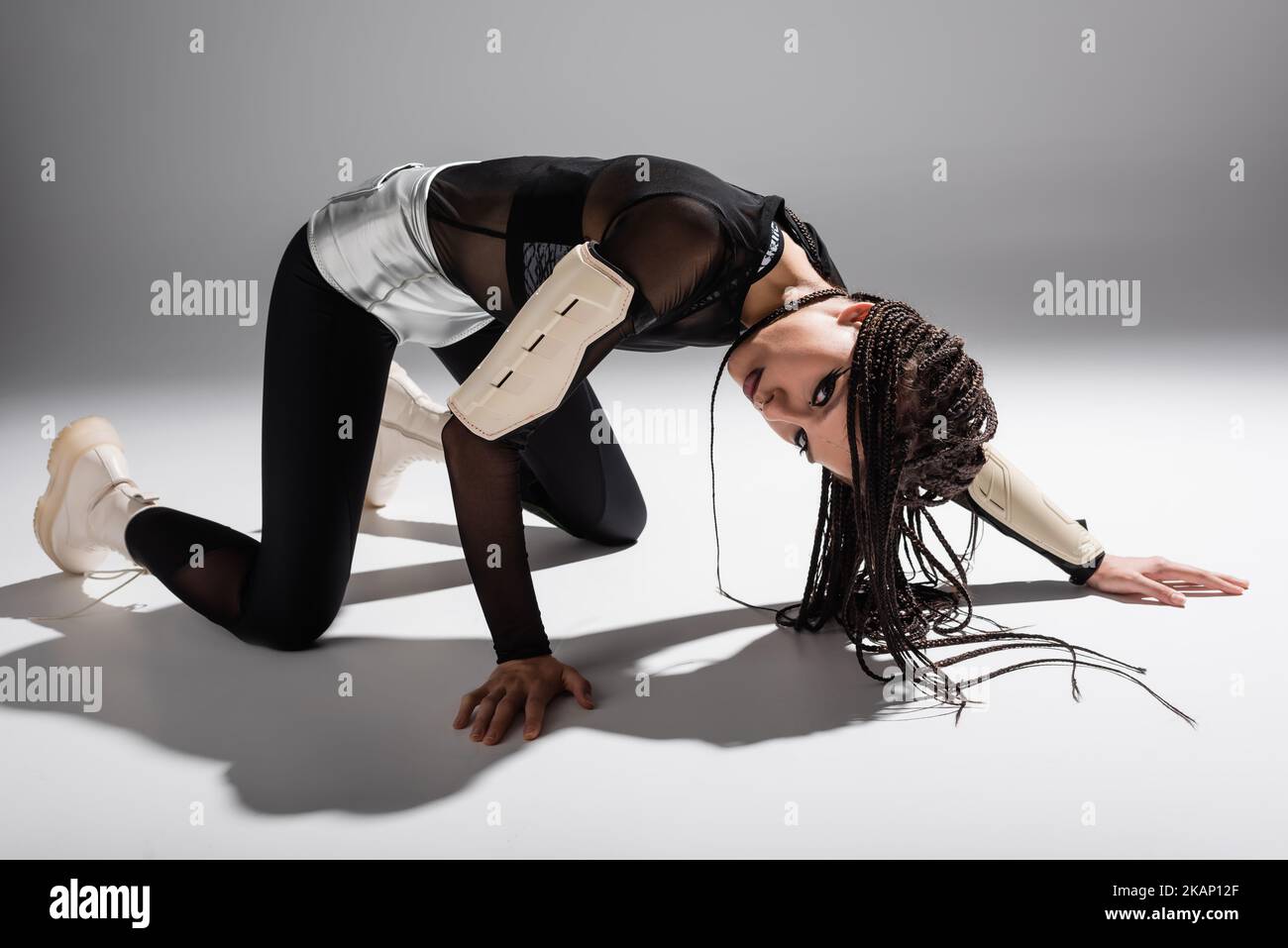 expressive woman with dreadlocks posing in futuristic outfit and ...