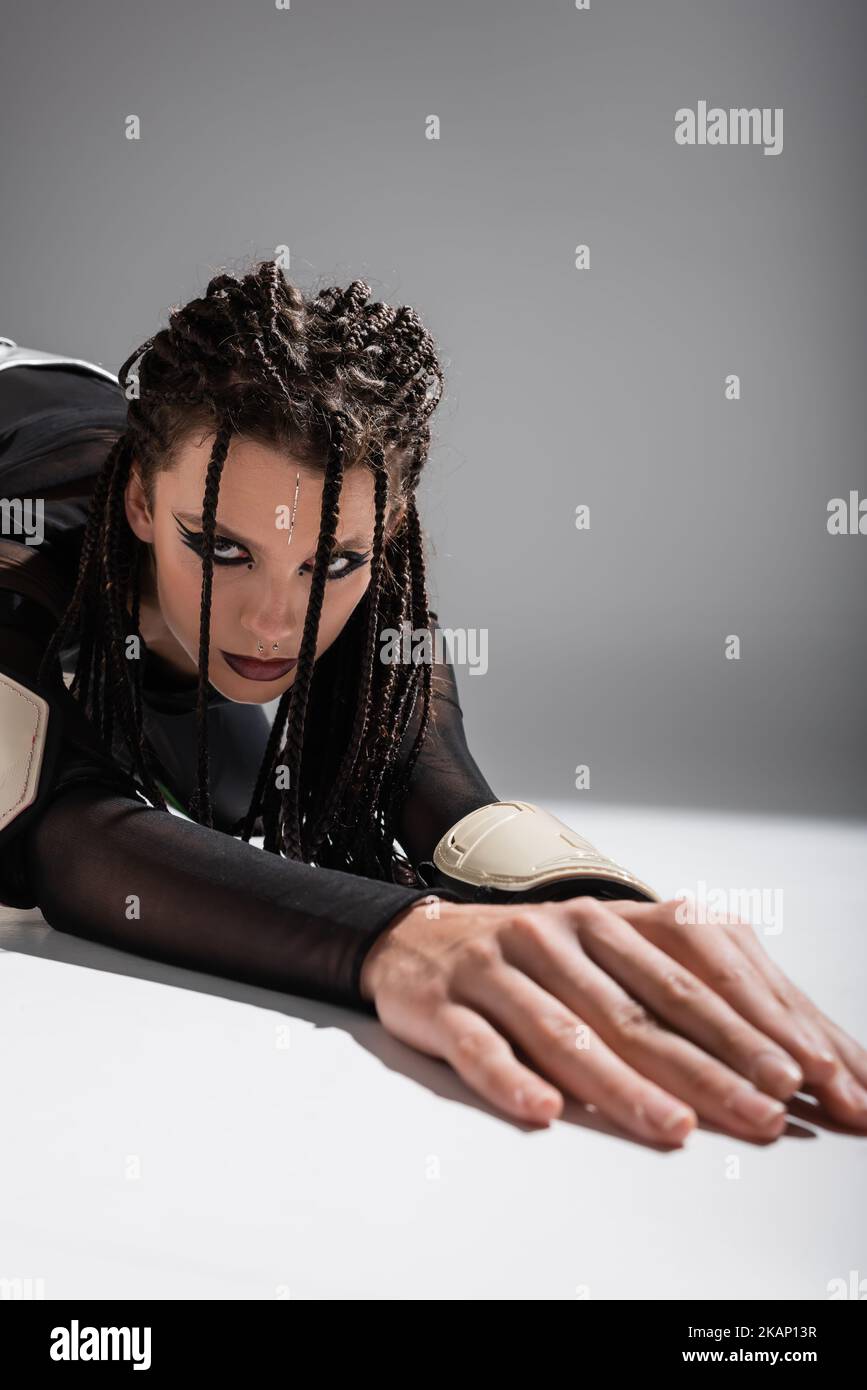 brunette woman with futuristic makeup and dreadlocks posing on white ...