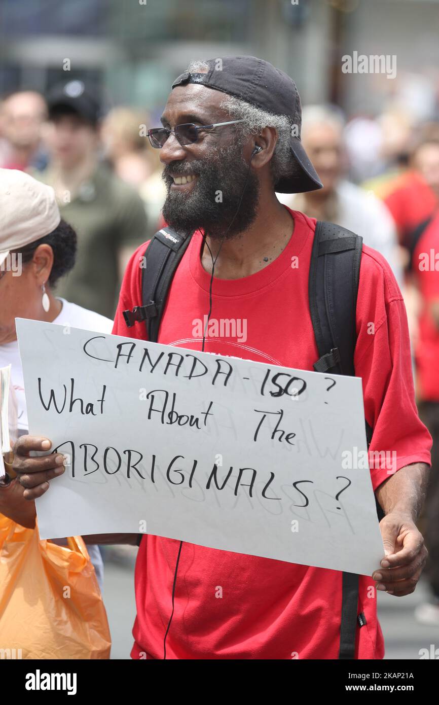 Man holds a sign protesting Canada Day and the 150th anniversary of ...