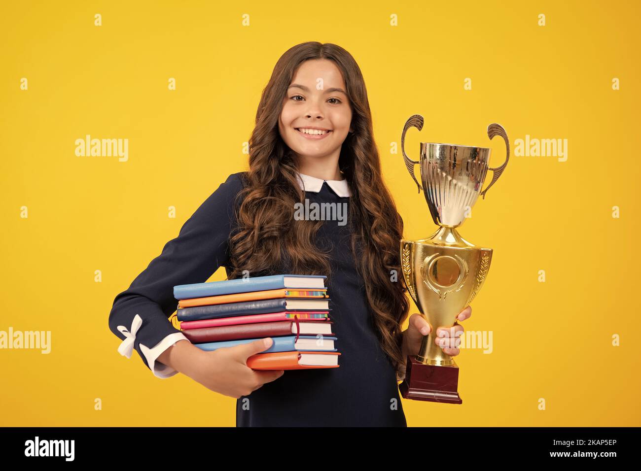 Schoolgirl in school uniform celebrating victory with trophy. Teen ...