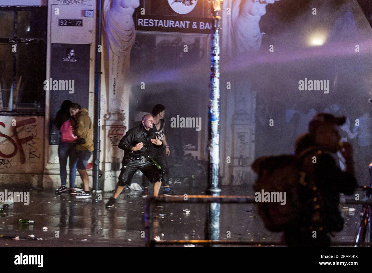 A demonstrator stand under the jet of a water cannon, in Hamburg, on ...