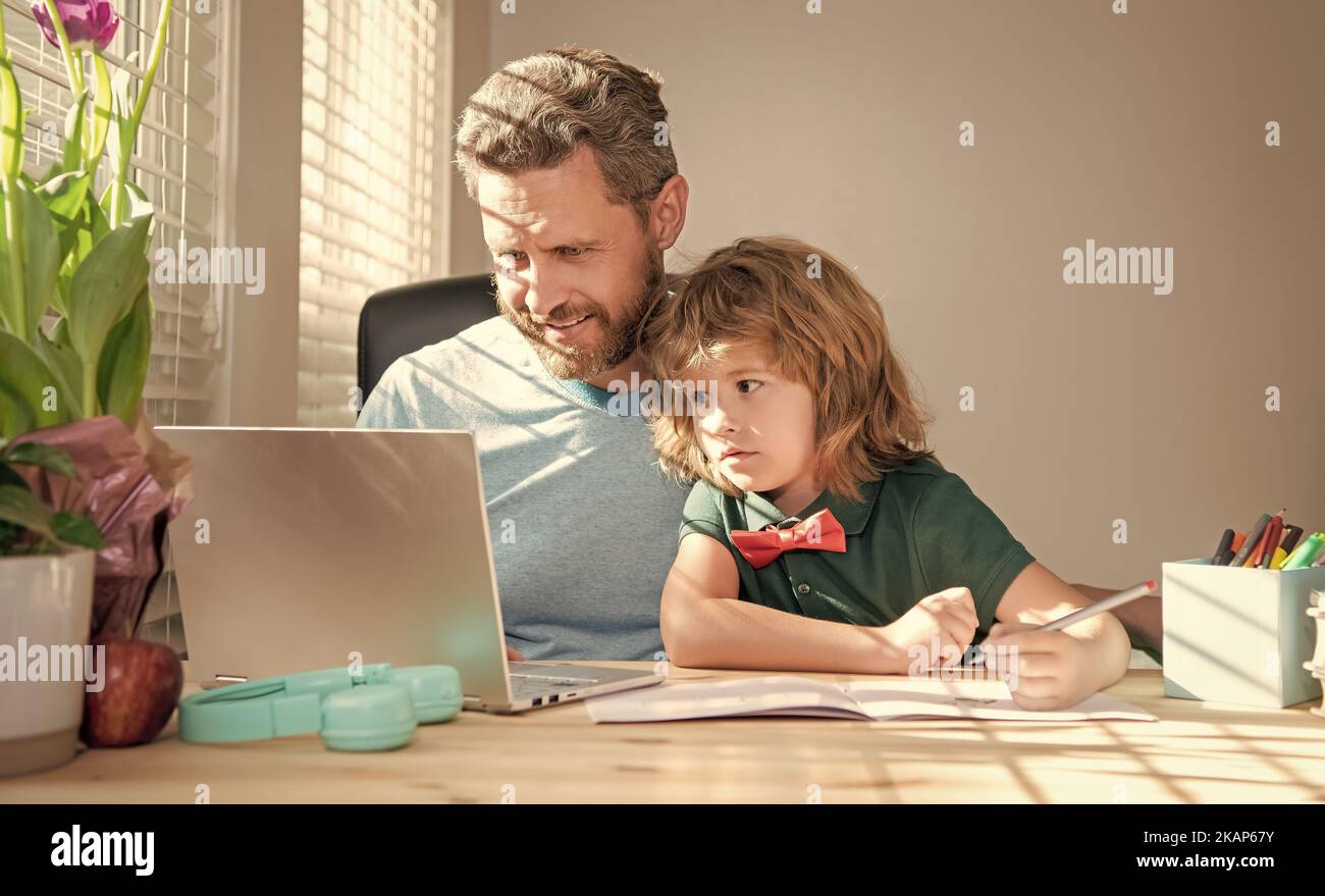 back to school. smiling father and son use computer at home. family and ...