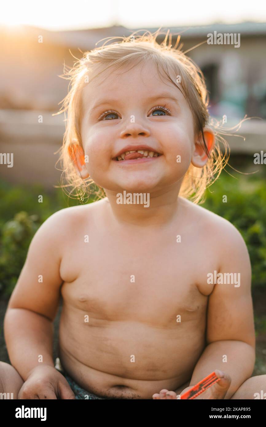 Portrait of adorable baby girl playing in the garden getting dirty ...