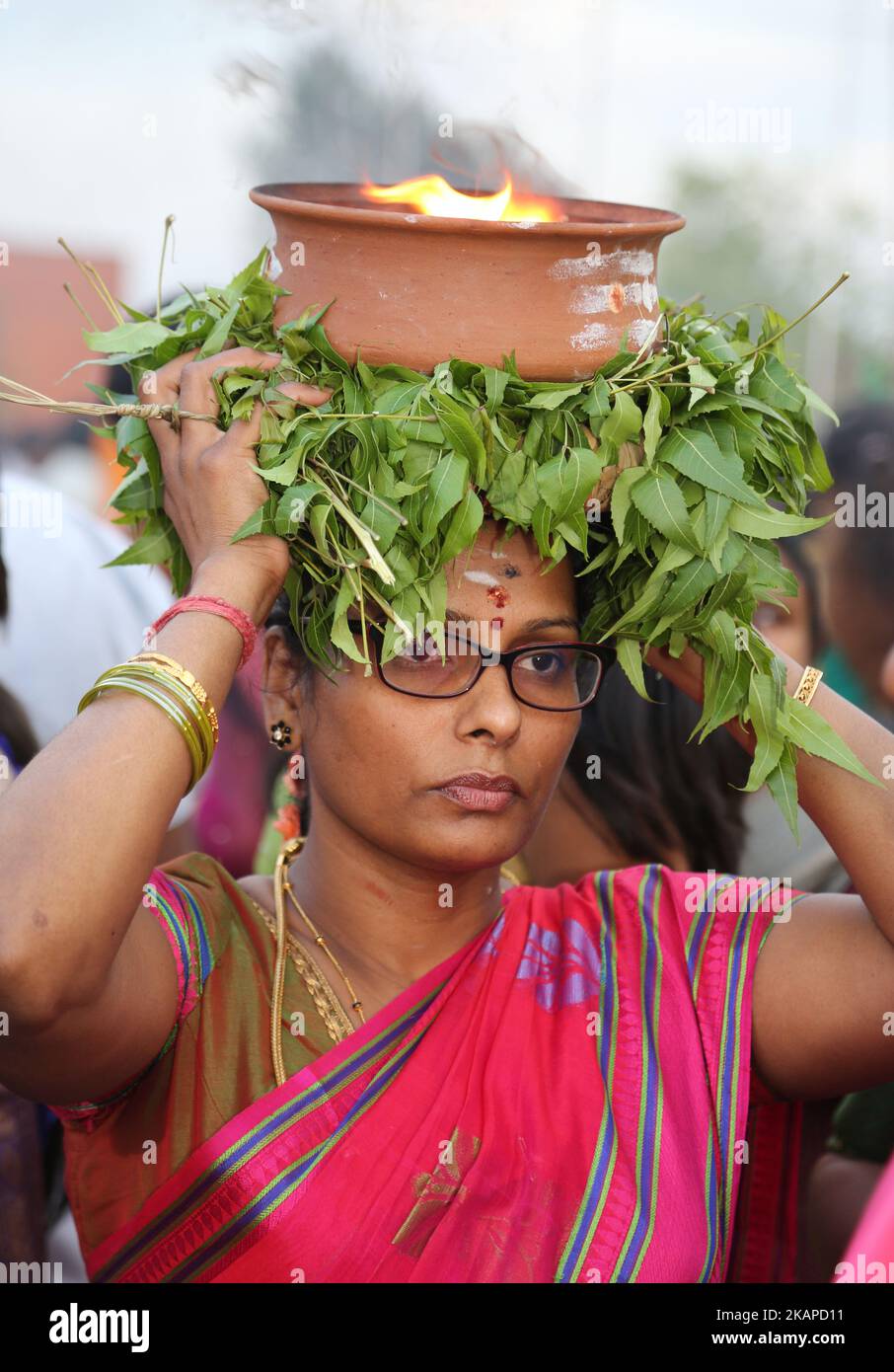 Tamil Hindu woman holds a clay pot with burning camphor atop margosa ...