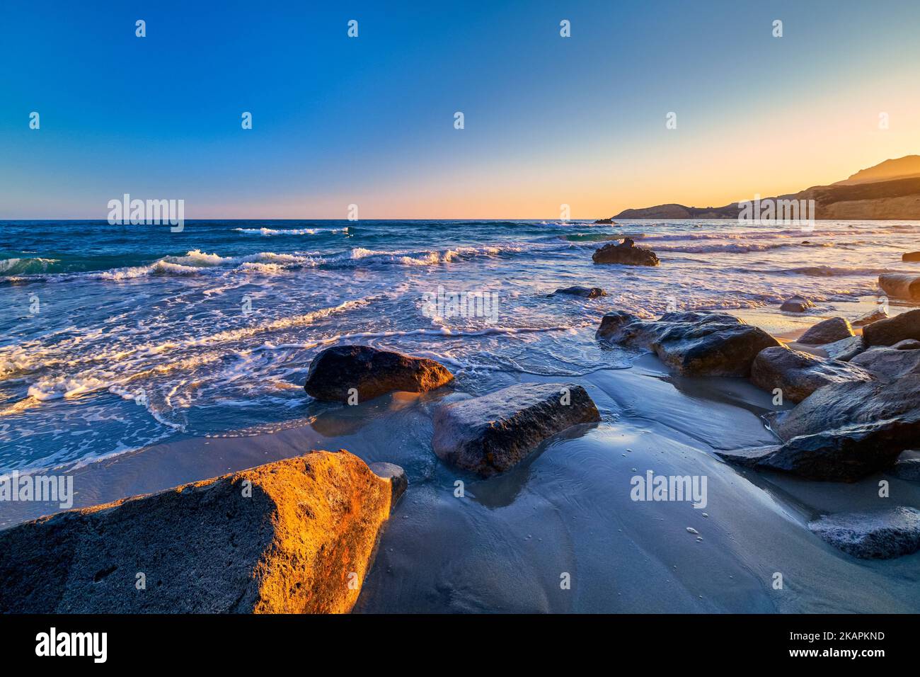Beautiful seascape of low tidal waves, clear sunset sky, hazy hills ...