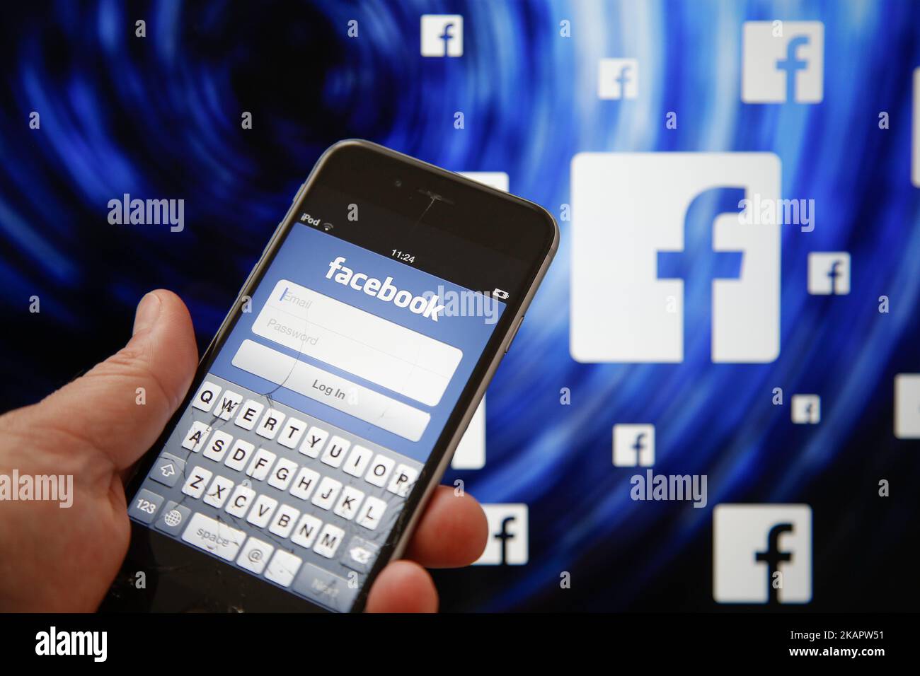 The Facebook logo is seen on an Apple iPhone with a cracked screen in ...