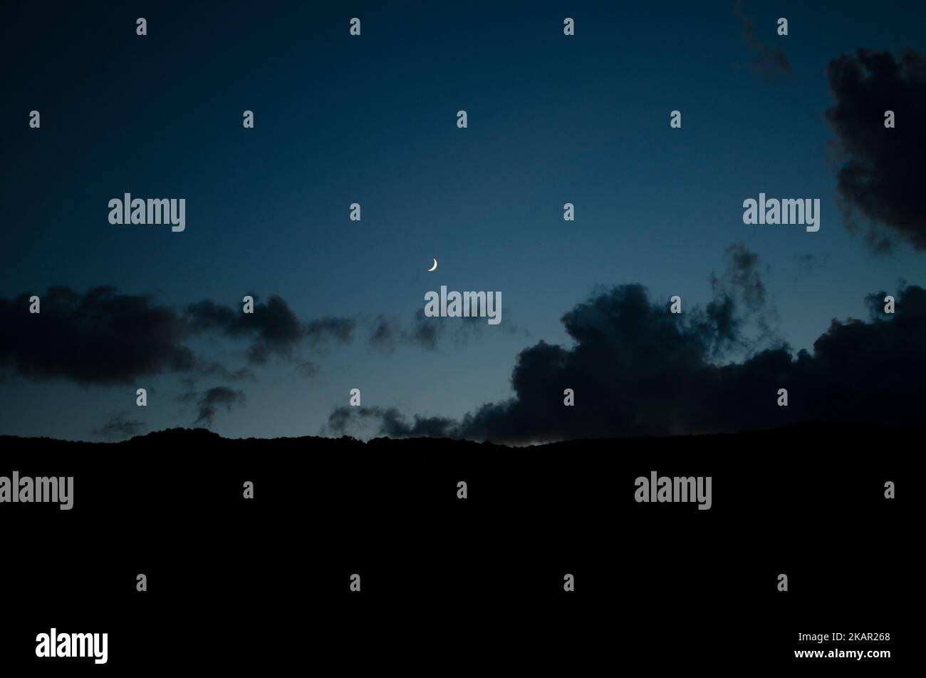 Crescent moon with some clouds at dusk Stock Photo - Alamy