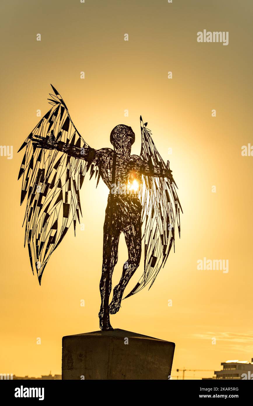 A vertical shot of a statue of an angel in sunset sky background in ...