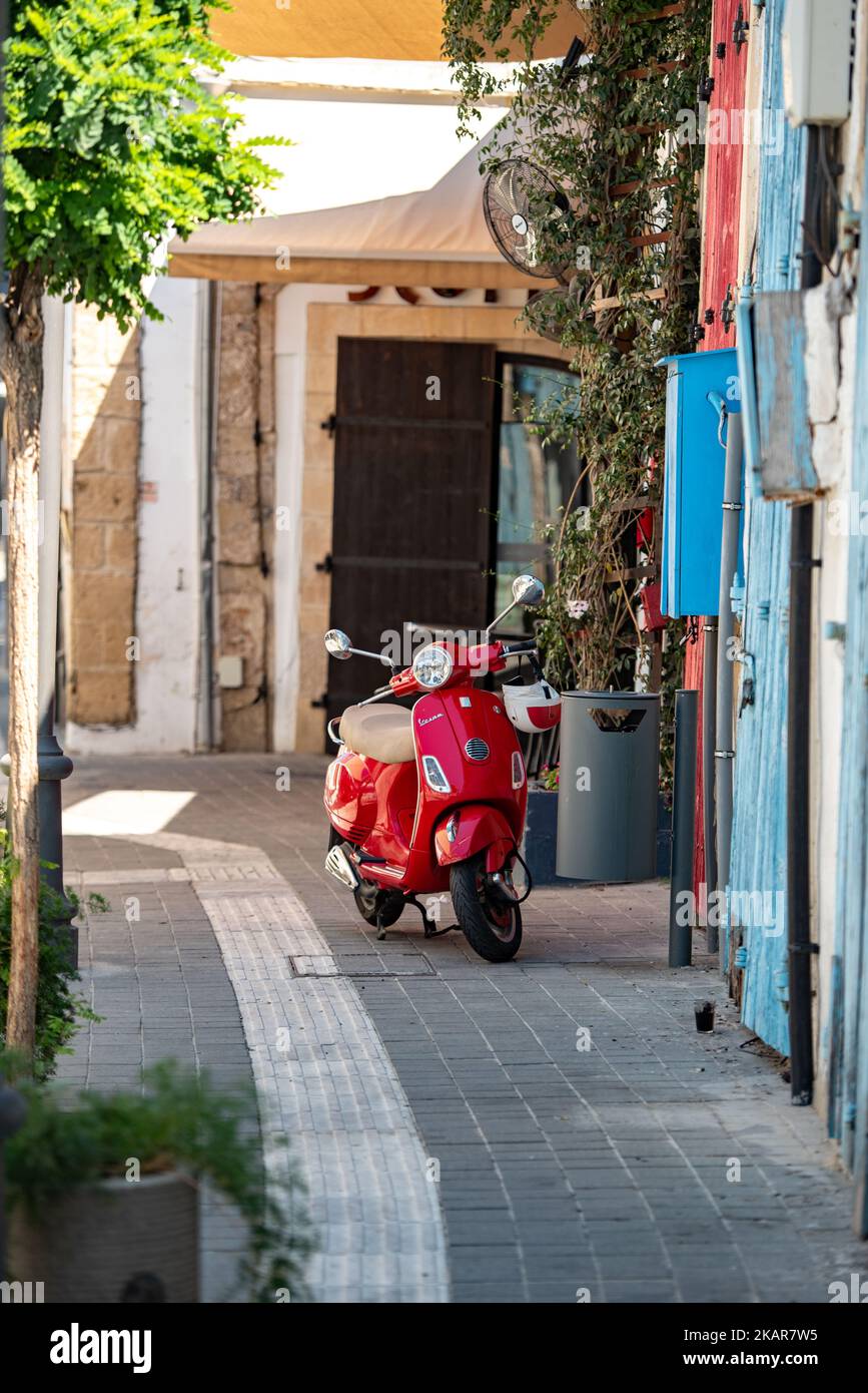 A vertical shot of a red old motorbike parked on the street in Cyprus ...
