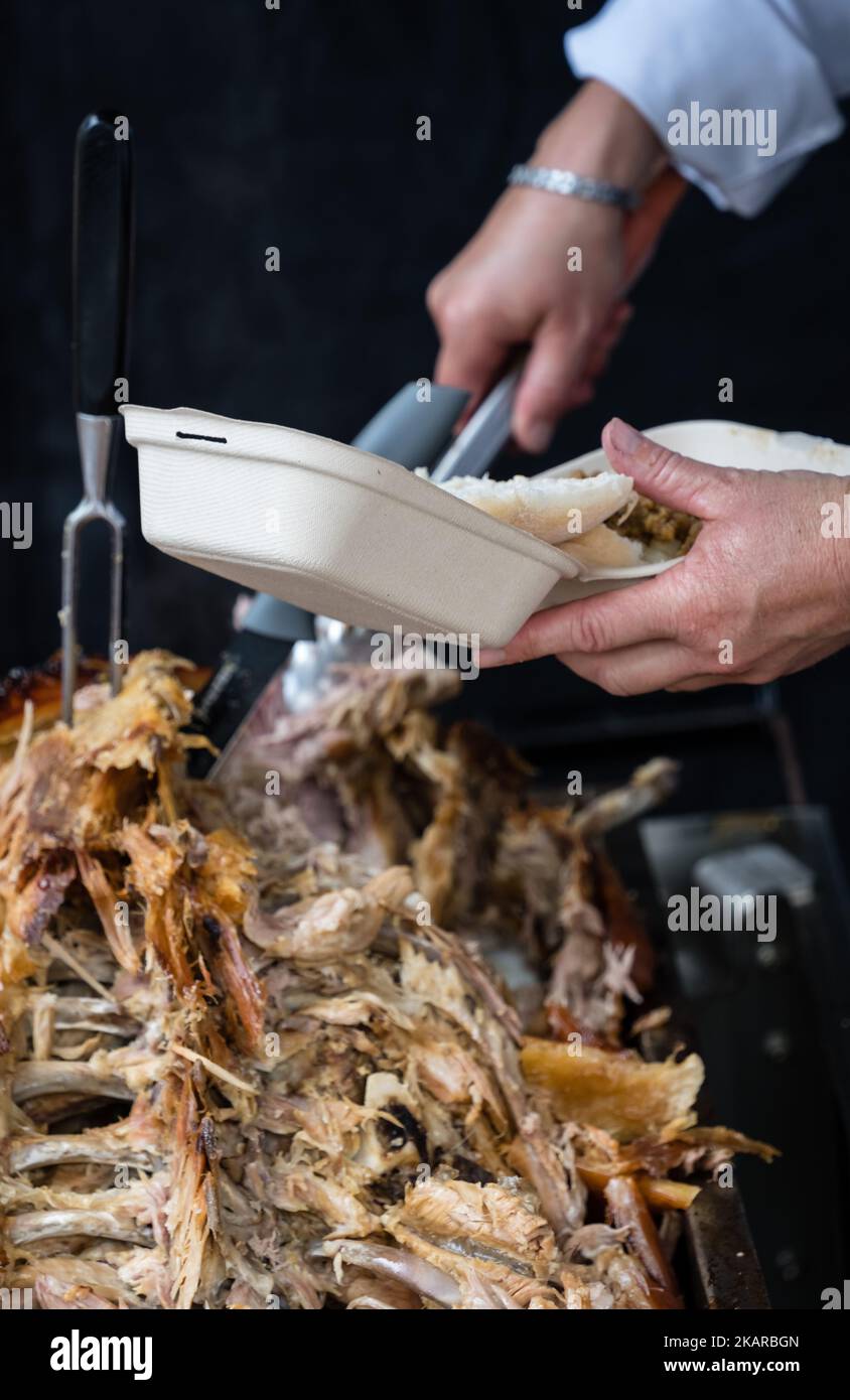 A vertical shot of a man putting pulled pork in his container Stock ...