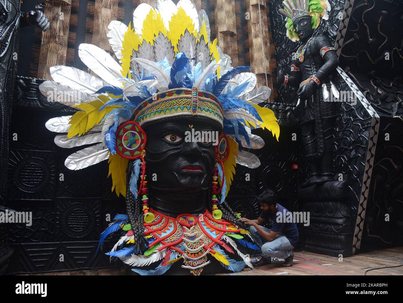 An Indian artisan prepares the statue of Red Indians in a Puja pandal ...