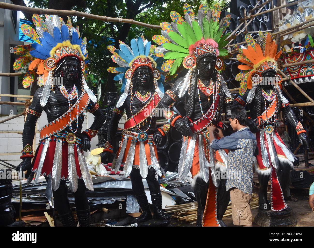 An Indian artisan prepares the statue of Red Indians in a Puja pandal ...