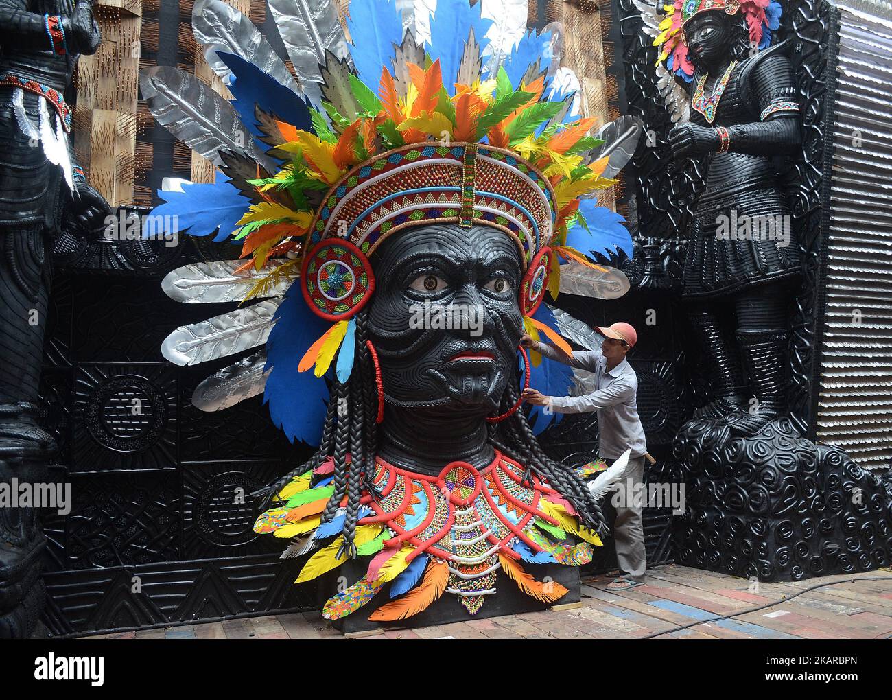 An Indian artisan prepares the statue of Red Indians in a Puja pandal ...