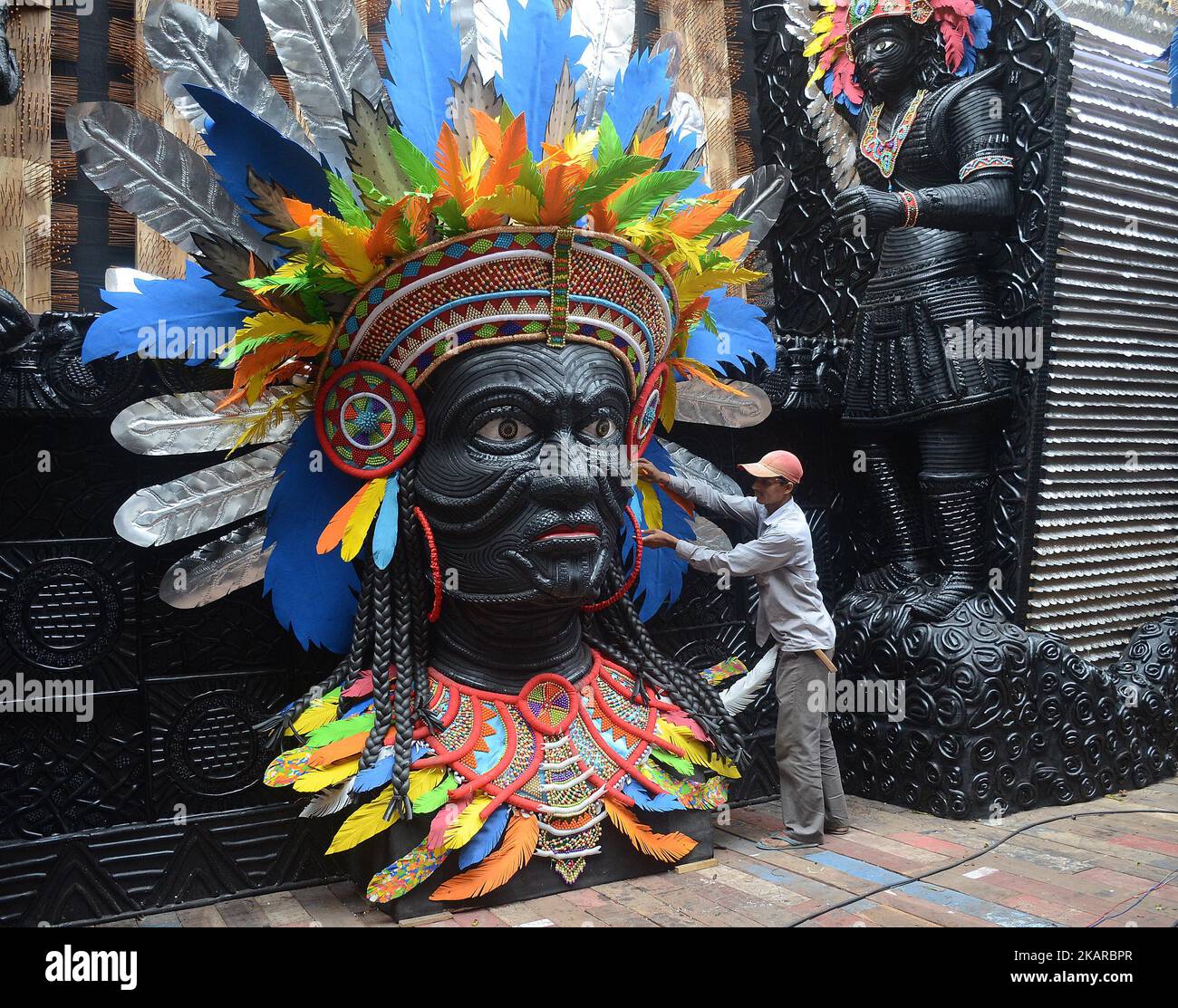 An Indian artisan prepares the statue of Red Indians in a Puja pandal ...