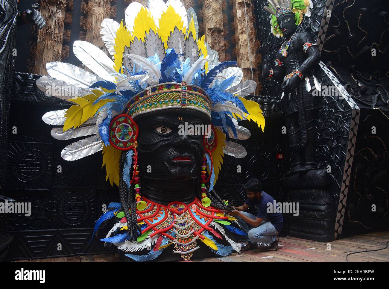 An Indian artisan prepares the statue of Red Indians in a Puja pandal ...