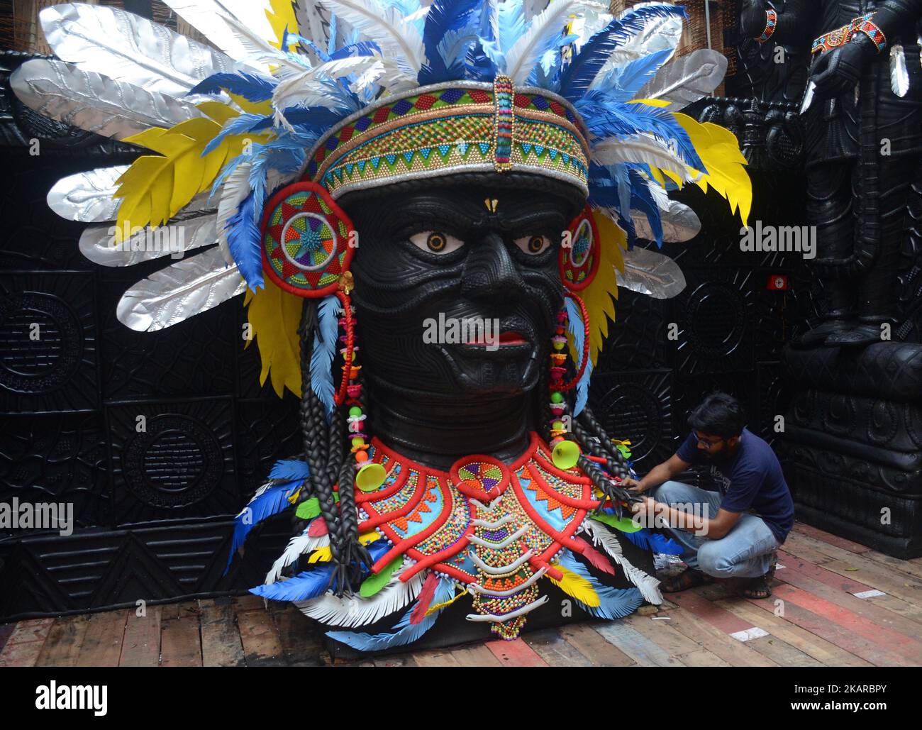 An Indian artisan prepares the statue of Red Indians in a Puja pandal ...