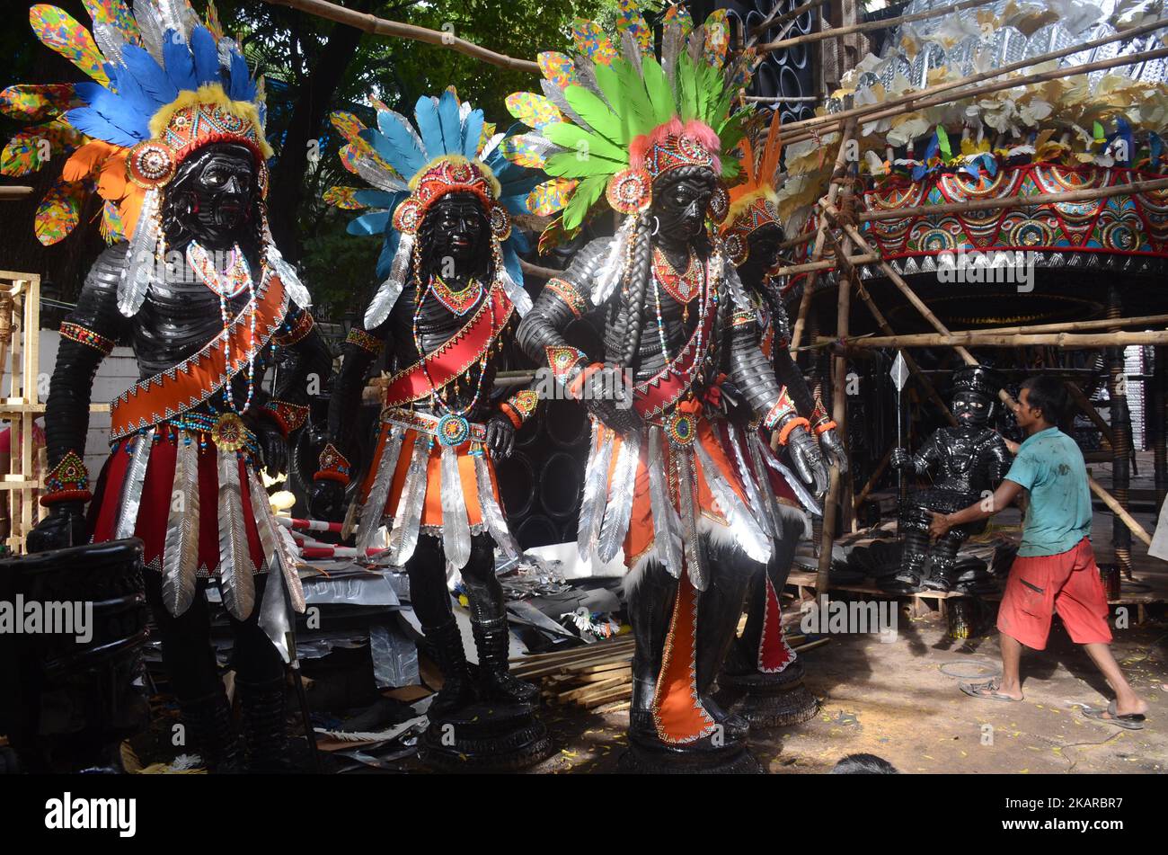 An Indian artisan prepares the statue of Red Indians in a Puja pandal ...
