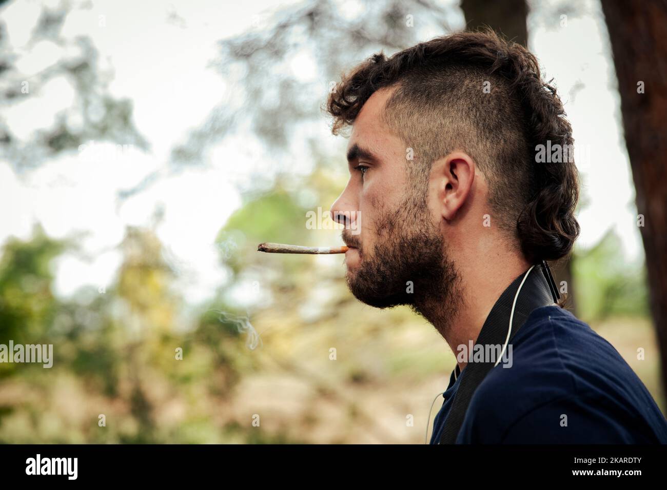 Close-up of a man smoking a marijuana cigarette in a forest Stock Photo ...