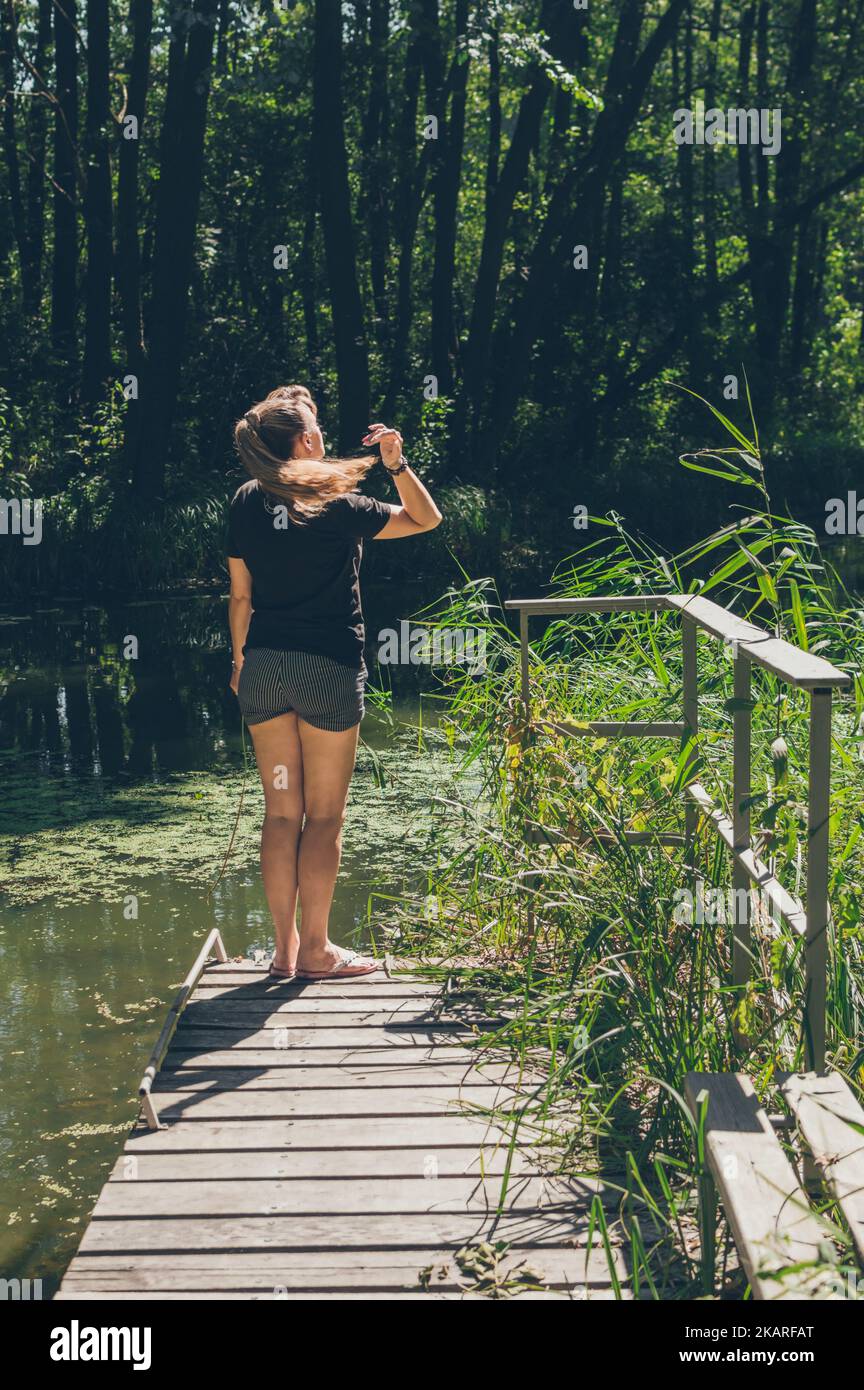 A woman in shorts throws her hair back, standing in sunlight Stock ...