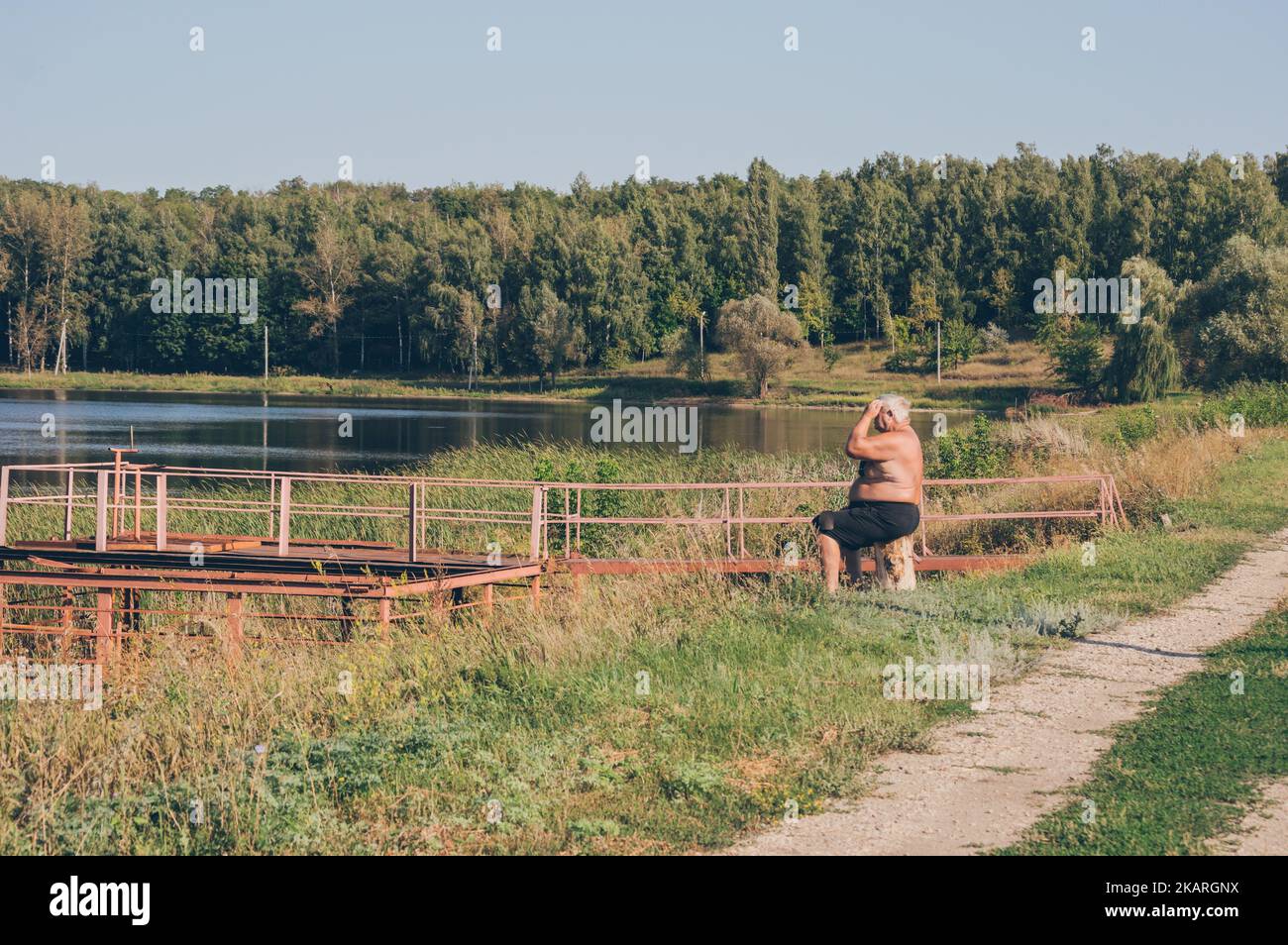 Old watchman sitting on high riverbank against forest landscape Stock ...