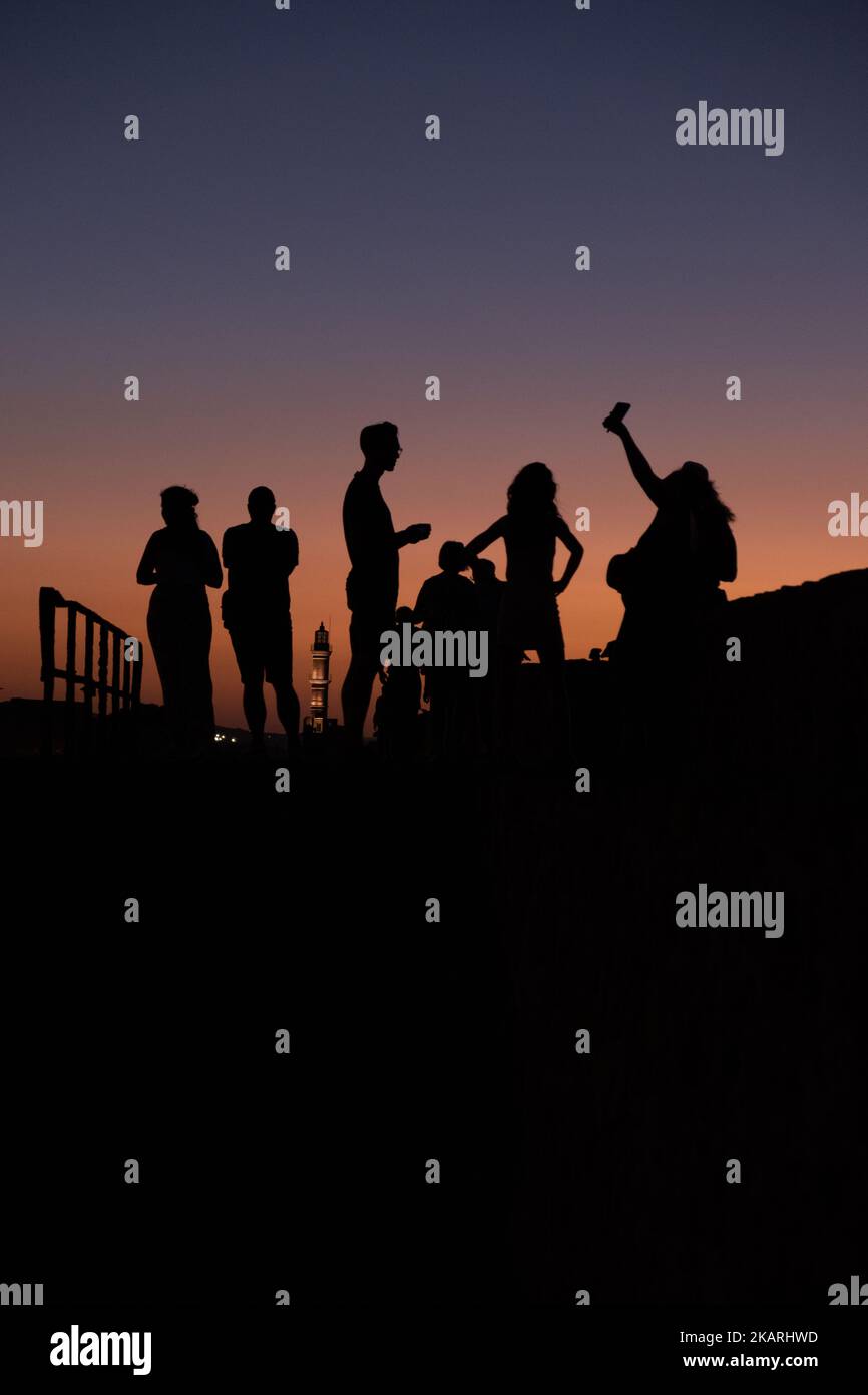 Silhouette of a group of people having fun on the sunset at the coast ...