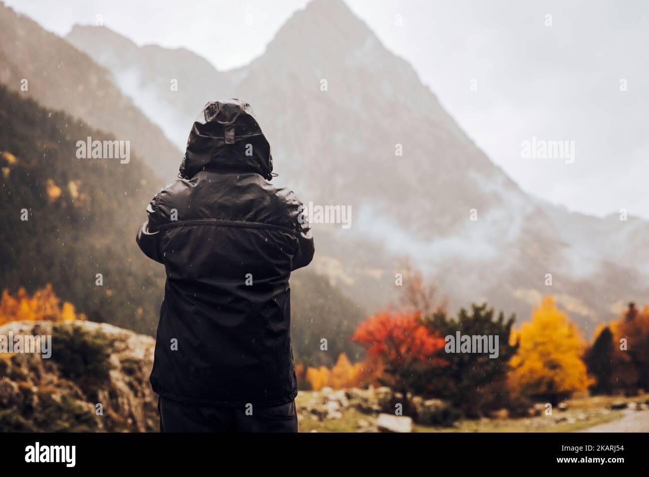 Boy in a raincoat taking photos of an autumn mountain landscape Stock ...