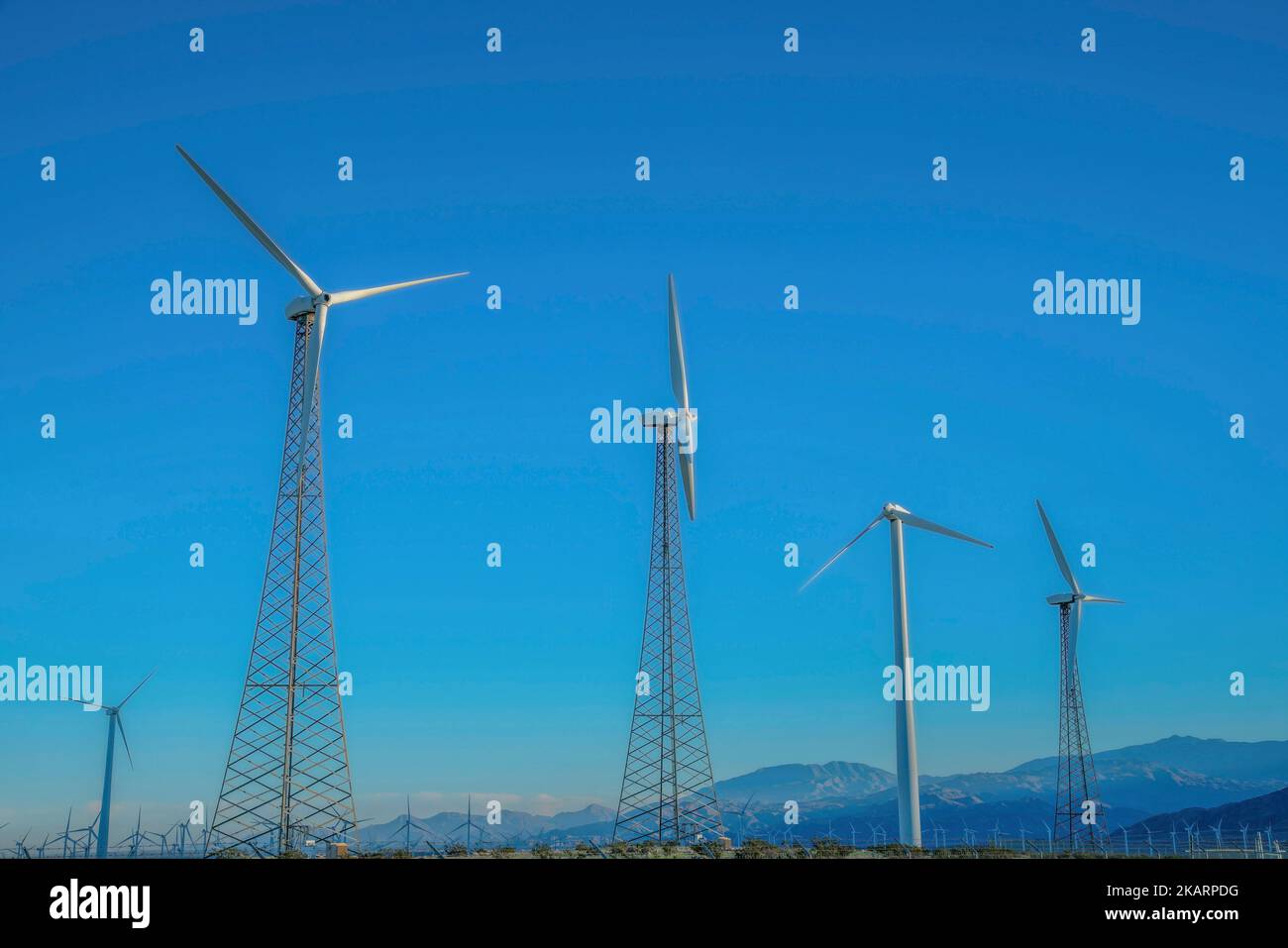 Windmill farm on a desert with tubular steel and lattice towers against ...