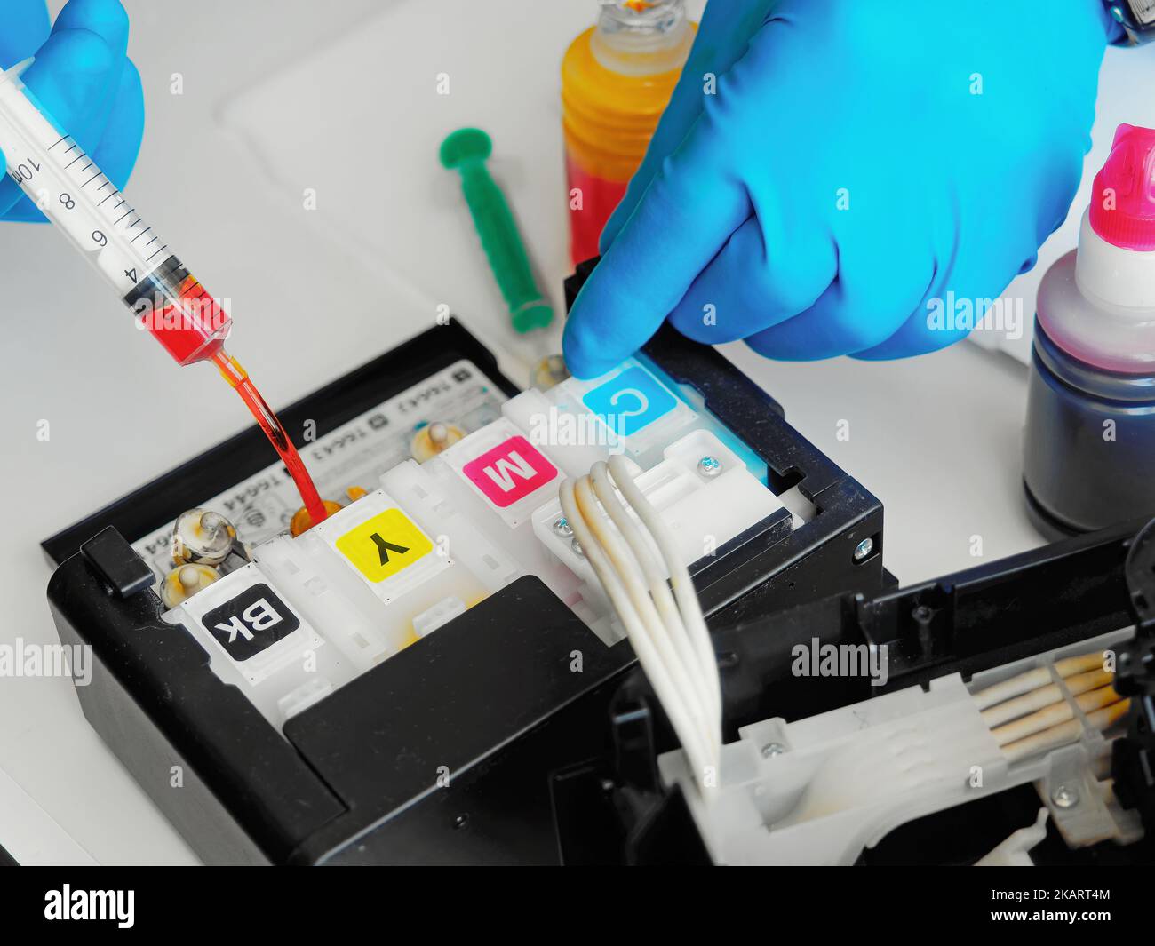 Printer maintenance. Master fills inkjet printer with ink or syringe ...