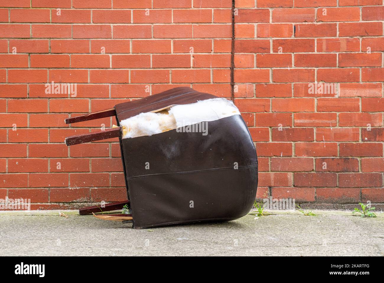 Bucket chair with broken leg abandoned in a street Stock Photo - Alamy